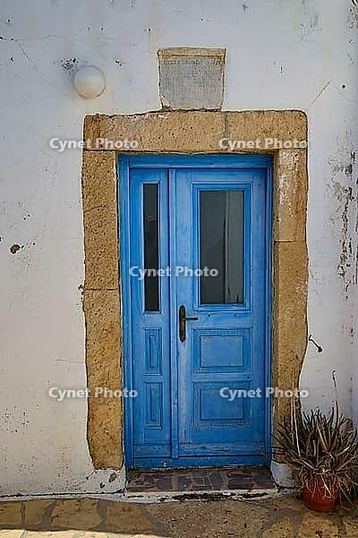 Blue entrance door with stone frame in a rustic building, main village ...