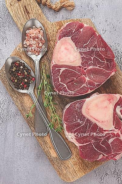 Freshly sliced beef legs, two ossobuco steaks, on a wooden board, with ...