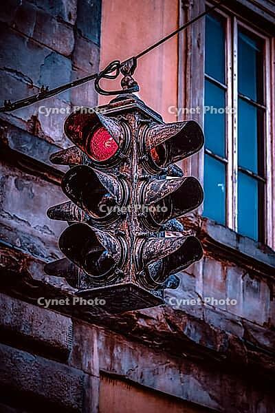 An old, weathered traffic light hangs in front of a building façade ...